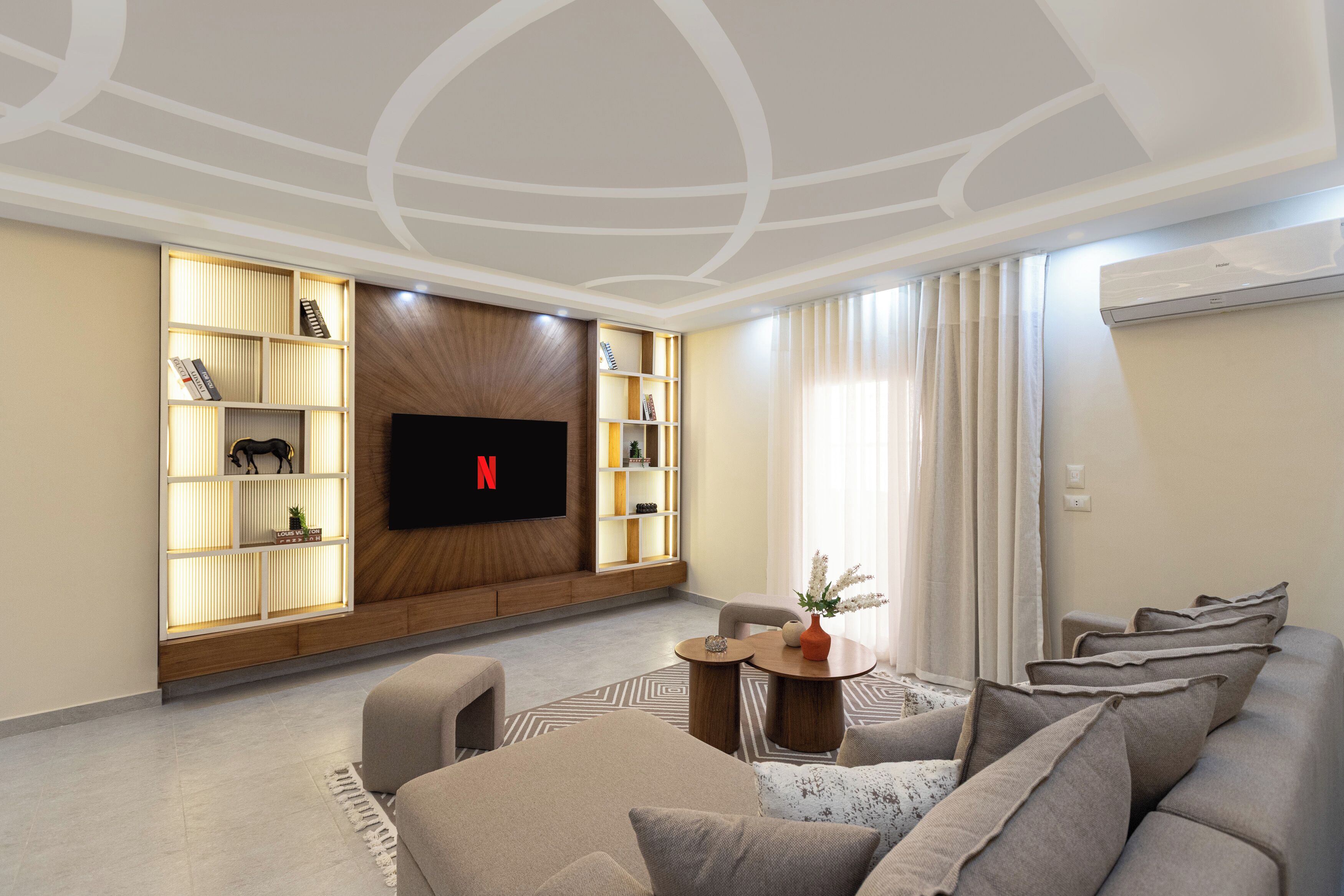 Uma sala de estar moderna com televisão de tela plana, estantes embutidas, um sofá e uma mesa de centro.