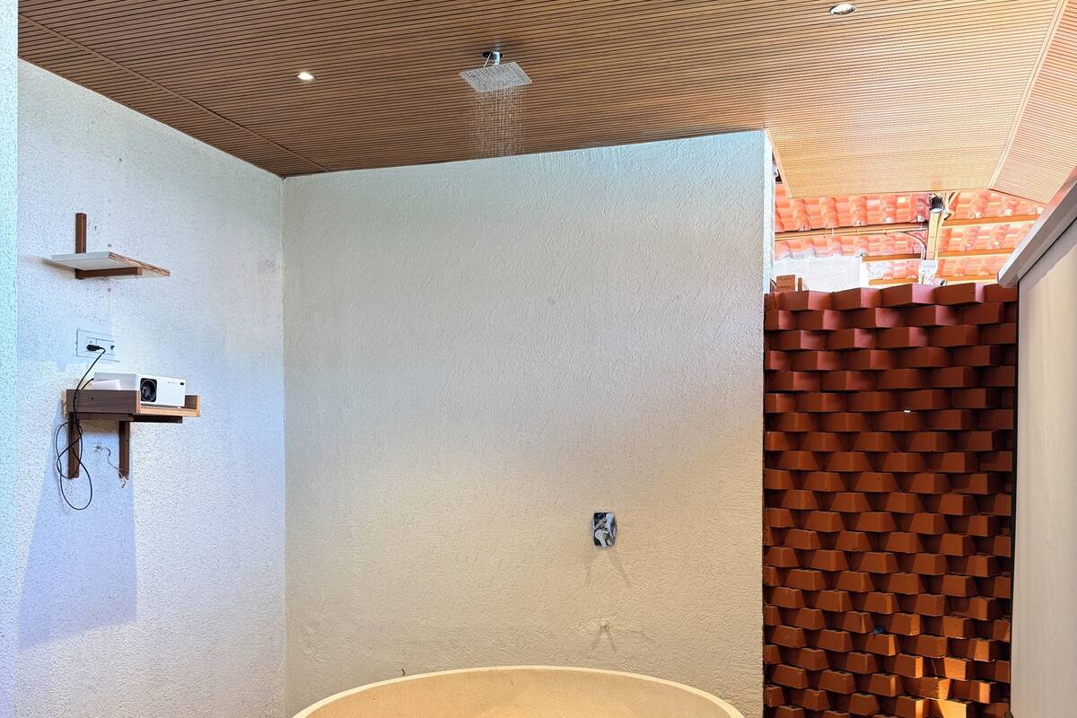 Um banheiro moderno com uma banheira circular grande, teto de madeira e parede com padrão de tijolos.