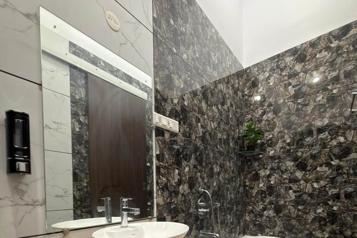 Uma casa de banho moderna com lavatório de mármore, um espelho grande e uma banheira.