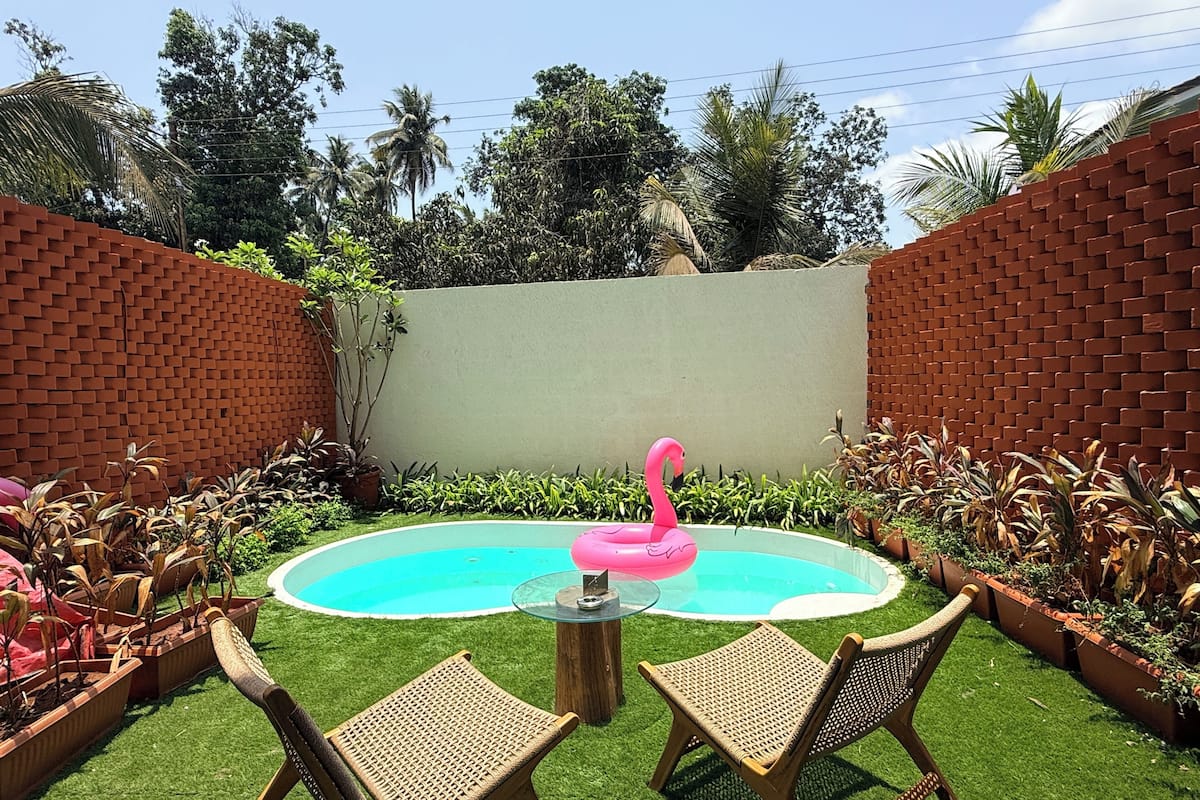 Um quintal com piscina, duas cadeiras de vime e um flutuador em formato de flamingo rosa.