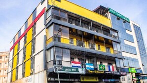 Um edifício de vários andares com varandas, um restaurante e diversos letreiros comerciais.