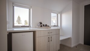 Uma cozinha compacta com geladeira Hisense, um balcão com cafeteira e uma janela com vista para árvores.
