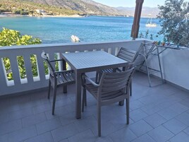 Um terraço com mesa e cadeiras, vista para um corpo de água e colinas.