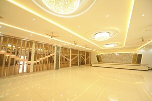 Um hall amplo com uma recepção de mármore, luminárias modernas e um ventilador de teto.