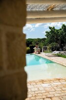 Uma piscina de pedra com espreguiçadeiras e um muro de pedra.