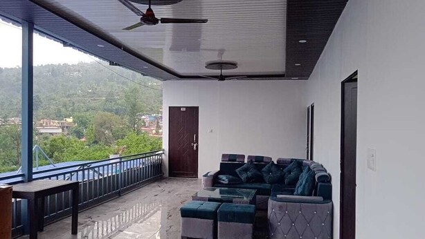 Uma varanda com área de estar, ventilador de teto e vista para a paisagem ao redor.