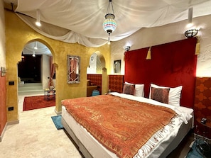 Quarto com uma cama grande, parede com destaque em vermelho e um lustre.