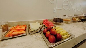 Buffet com diversas frutas e sobremesas em bancada de mármore.