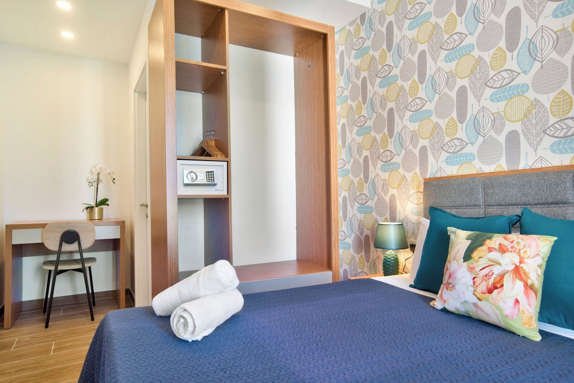 Um quarto com cama, escrivaninha, cadeira e guarda-roupa.