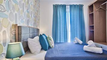Quarto com cama, almofadas, abajur, guarda-roupa e cortinas.