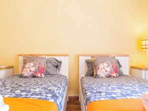 Duas camas com almofadas estampadas de flores e colchas com padrão circular.