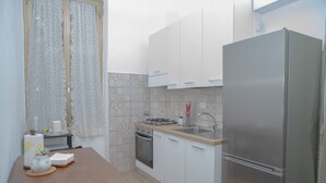 Uma cozinha compacta com armários brancos, geladeira de aço inoxidável, fogão a gás e pia.