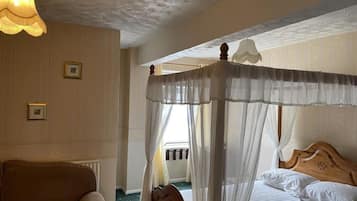 Quarto com cama de dossel, sofá e luminária no teto.