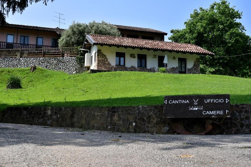 Um edifício com parede de pedra e uma placa indicando direções para Cantina, Ufficio e Camera.