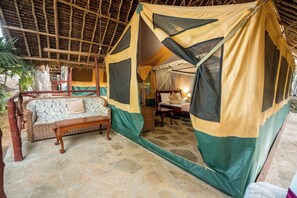 Acomodação em tenda com cama, sofá e mesa.