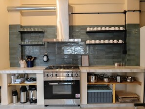 Cozinha equipada com fogão a gás, forno e diversos utensílios e eletrodomésticos.