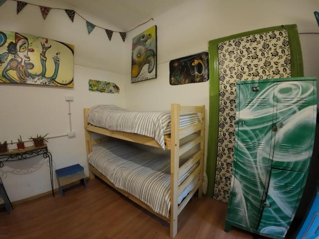 Um quarto com beliches, uma escrivaninha com plantas em vasos e um refrigerador.