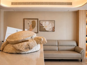 Quarto com uma escultura grande sobre uma mesa, um sofá bege e duas obras de arte emolduradas na parede.