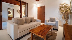 Uma sala de estar moderna com um sofá bege, uma mesa de centro de madeira e uma poltrona branca.