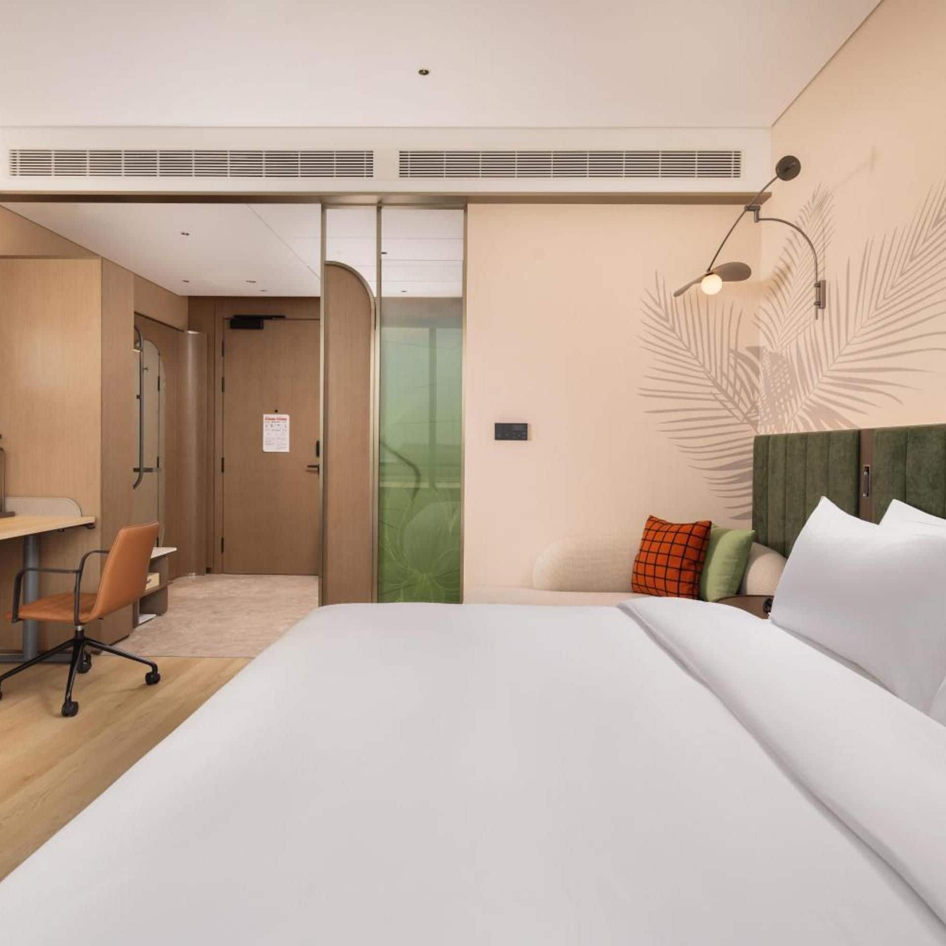 Quarto de hotel com cama, escrivaninha e cadeira.