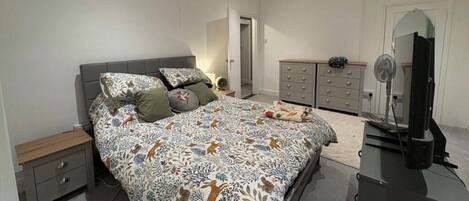 Quarto com cama, mesas de cabeceira, cômoda, espelho e aquecedor.