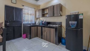 Uma cozinha compacta com armários escuros, geladeira e painel de azulejos.