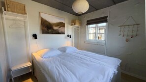 Quarto com cama, janela, luminária na parede e um quadro.