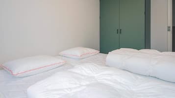 Quarto com cama, almofadas e um guarda-roupa verde.