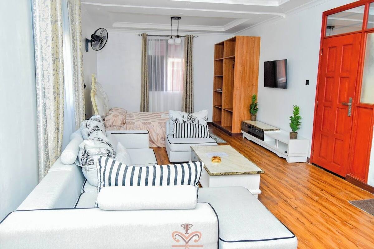 Uma sala de estar moderna com um sofá seccional, uma mesa de centro e uma TV fixada na parede.