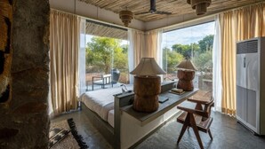 Quarto moderno com uma cama grande, uma escrivaninha de madeira e vista para o exterior.