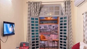 Quarto de hotel com cama, televisão, cadeira e mesa.