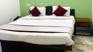 Quarto de hotel com cama, paredes verdes e mesa de cabeceira.