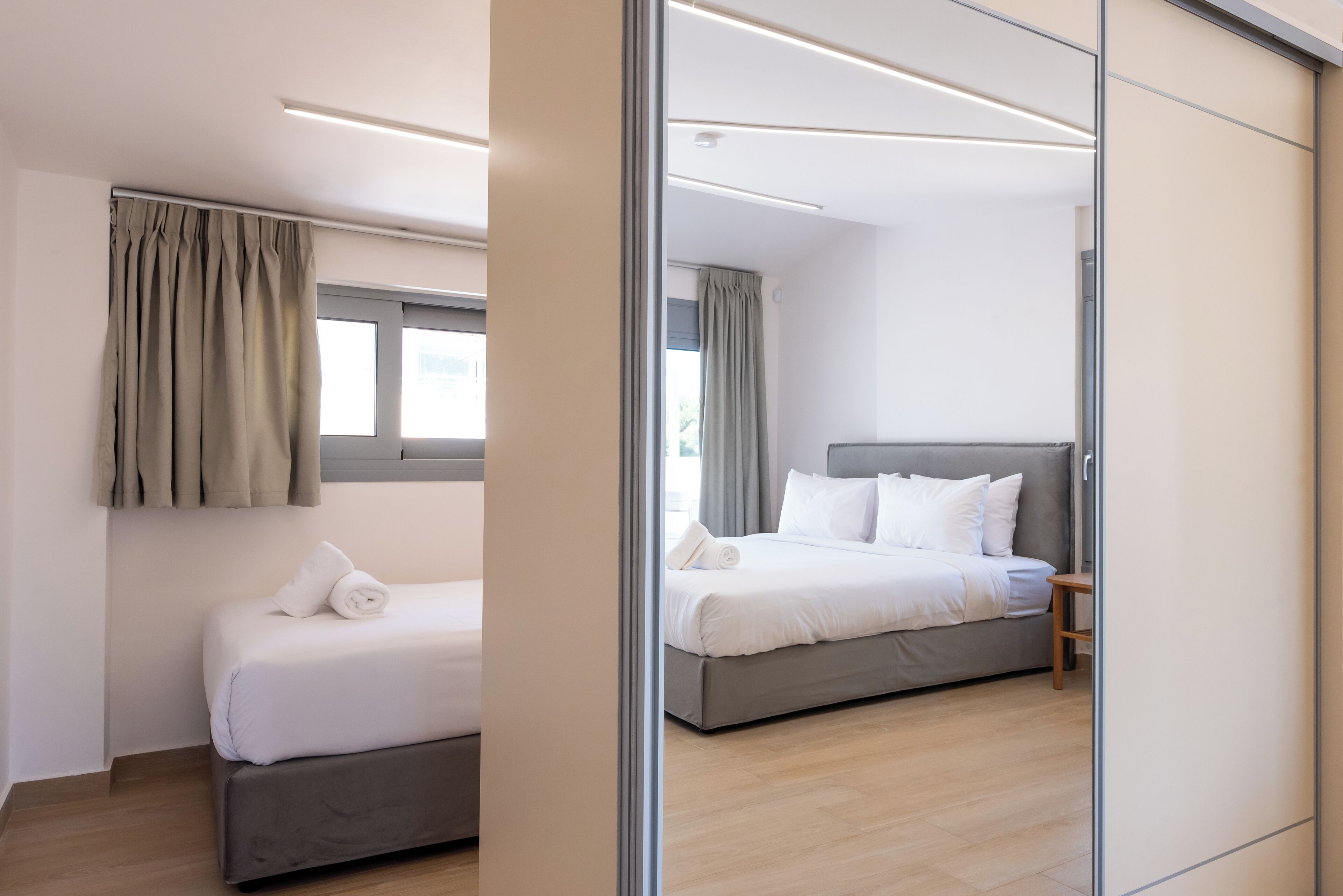 Quarto de hotel moderno com uma cama, mesa de cabeceira pequena e um espelho grande.