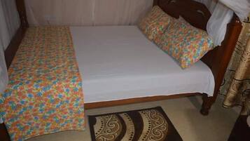 Uma cama de solteiro com colcha floral, almofada combinando e um tapete decorativo.