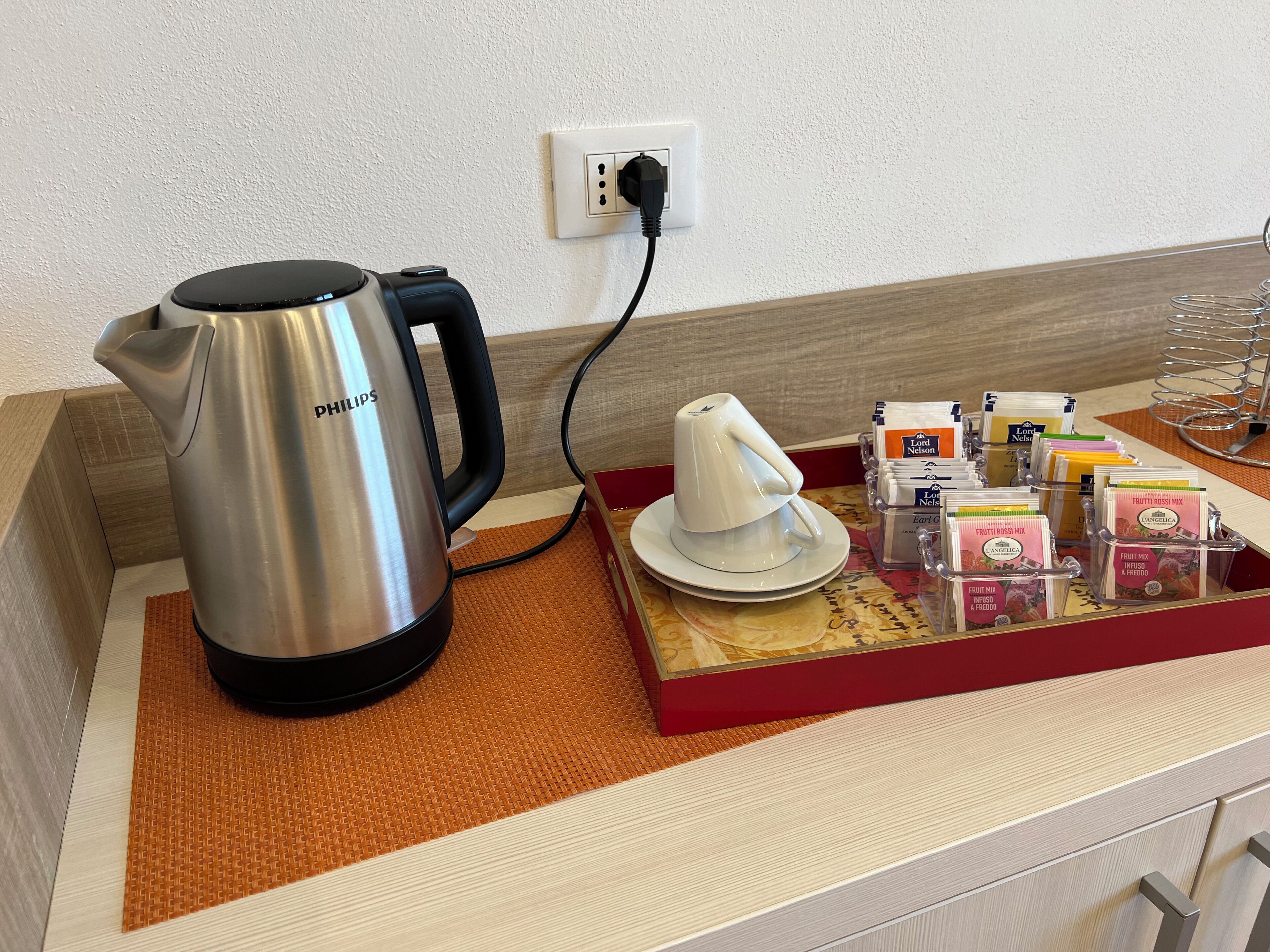 Uma área de cozinha com uma chaleira Philips de aço inoxidável, um bule branco e uma bandeja com saquinhos de chá e uma caixa de chá Earl Grey.