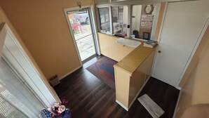 Um quarto pequeno com cozinha compacta, porta para o exterior e janela com vista para a rua.