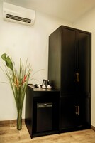 Um armário preto com puxadores dourados, um eletrodoméstico pequeno preto e uma planta com folhas verdes e flores vermelhas.
