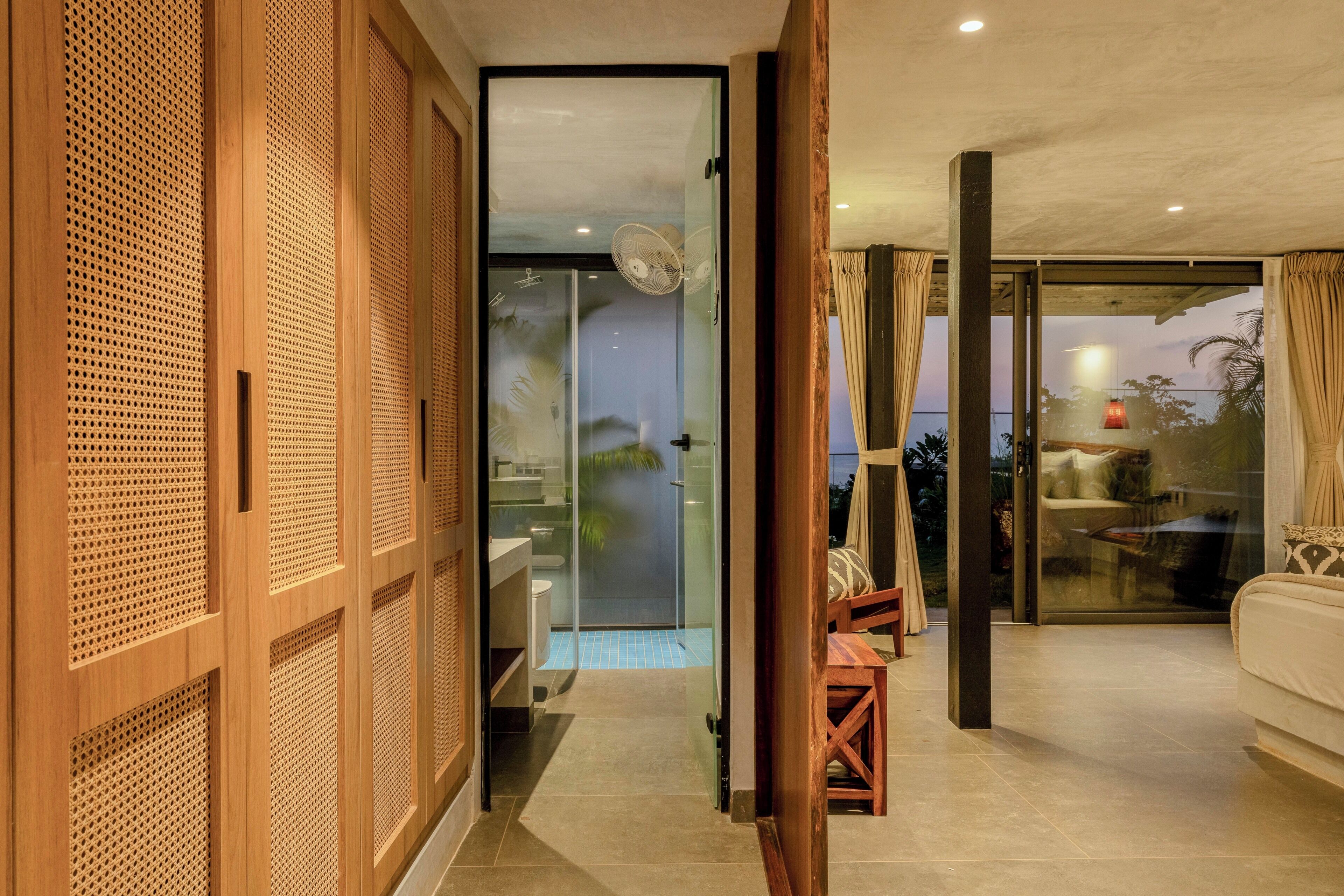 Um interior moderno com uma porta de vidro que dá para um banheiro, um ventilador e vista para o exterior.