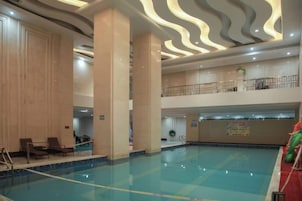 Uma grande piscina interior com design de teto ondulado, vários níveis e vista para o andar superior.