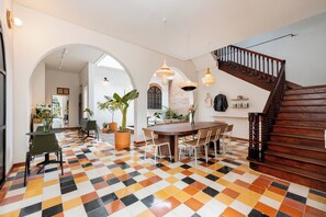 Uma ampla sala de jantar com piso xadrez, escada de madeira e parede de tijolos.