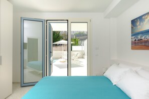 Quarto com cama, porta de vidro deslizante para uma varanda e um quadro na parede.