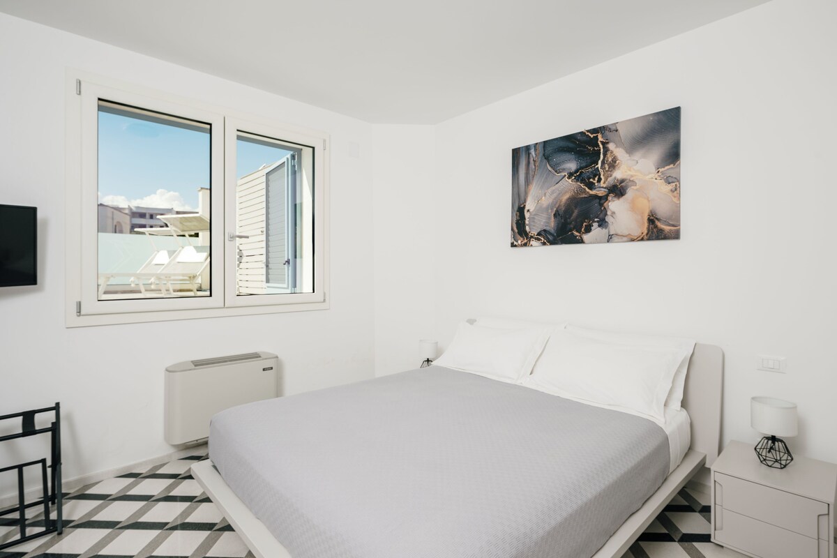Quarto com cama, janela, radiador e um quadro na parede.