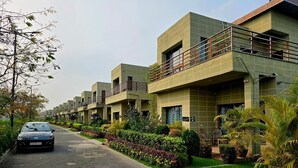 Uma fileira de edifícios modernos com varandas, uma rua pavimentada e jardins ajardinados.