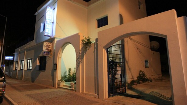 Um hotel com placa indicando ser uma unidade de 4 estrelas, apresentando uma entrada imponente com arco e portão.