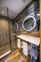 Uma casa de banho moderna com cabine de duche em vidro, toucador com espelho e porta-toalhas.