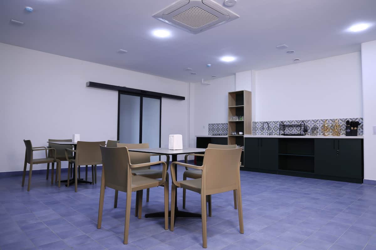Uma cozinha moderna com área de jantar, com uma mesa e cadeiras, bancada com prateleiras e painel de azulejos.