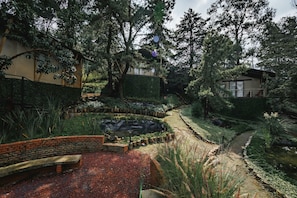 Um jardim com lago, um banco de tijolos e um caminho.