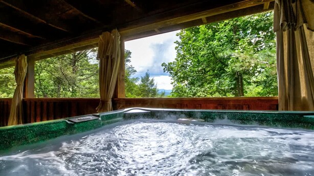 Banheira de hidromassagem com vista para uma área arborizada.