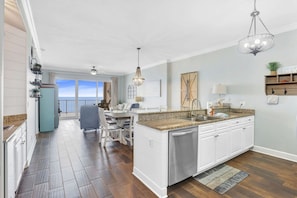 Uma cozinha espaçosa com uma ilha grande, armários brancos e vista para o exterior.