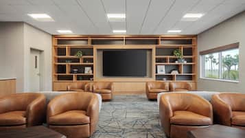 Uma sala de conferências com uma grande televisão de tela plana, poltronas de couro, estantes embutidas e piso carpeteado.